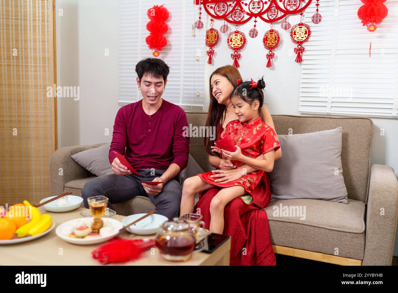 A Chinese family watches their child excitedly open a red envelope ...