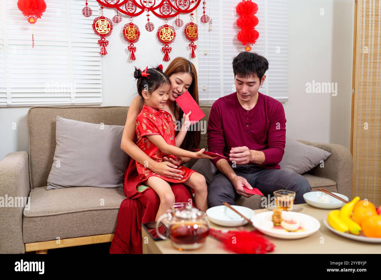 A Chinese family watches their child excitedly open a red envelope ...