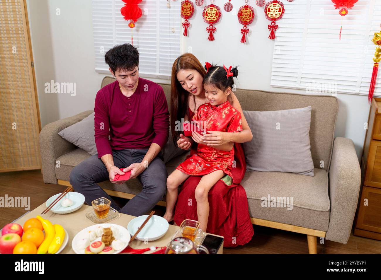 A Chinese family watches their child excitedly open a red envelope ...