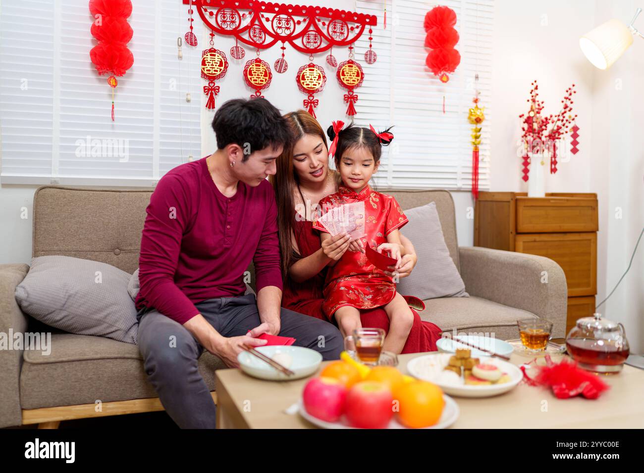 A Chinese family watches their child excitedly open a red envelope ...