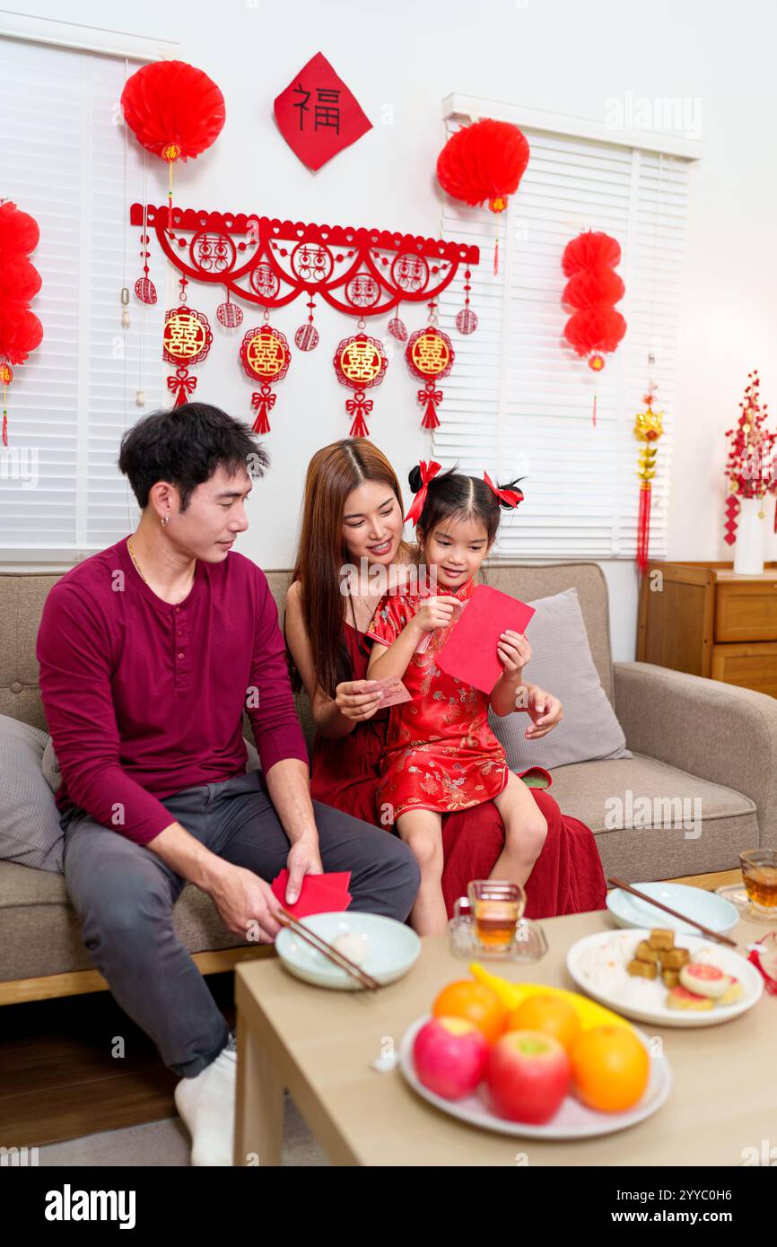 A Chinese family watches their child excitedly open a red envelope ...