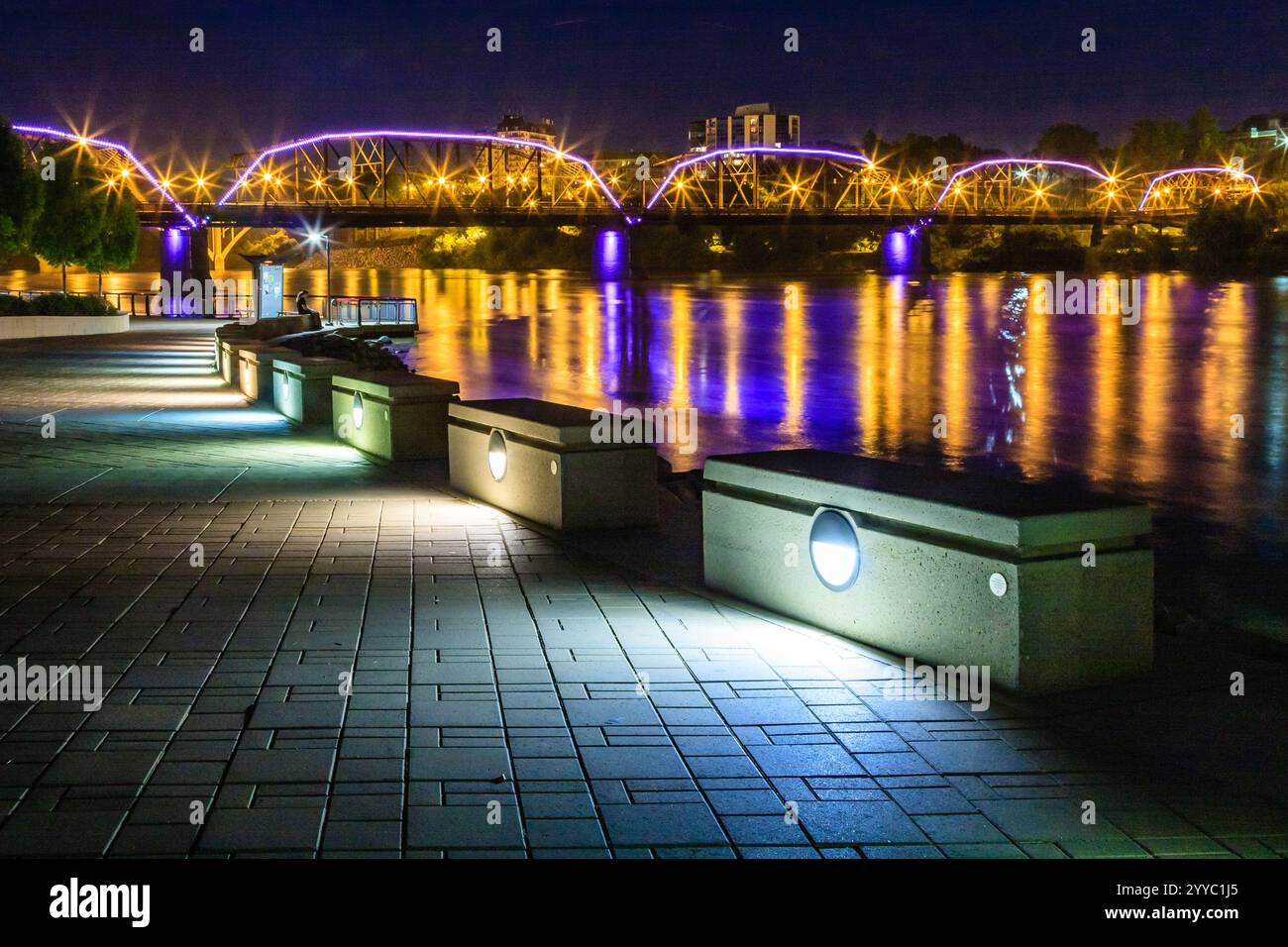 A beautiful bridge over a river, with lights illuminating the bridge ...
