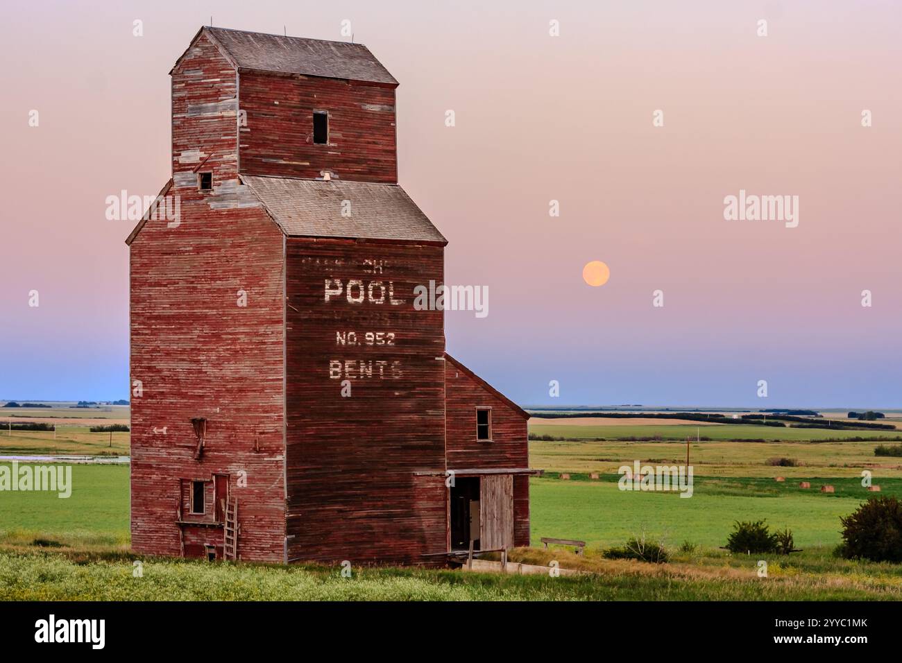 A red grain silo with the words Pool on it. The silo is in a field with ...