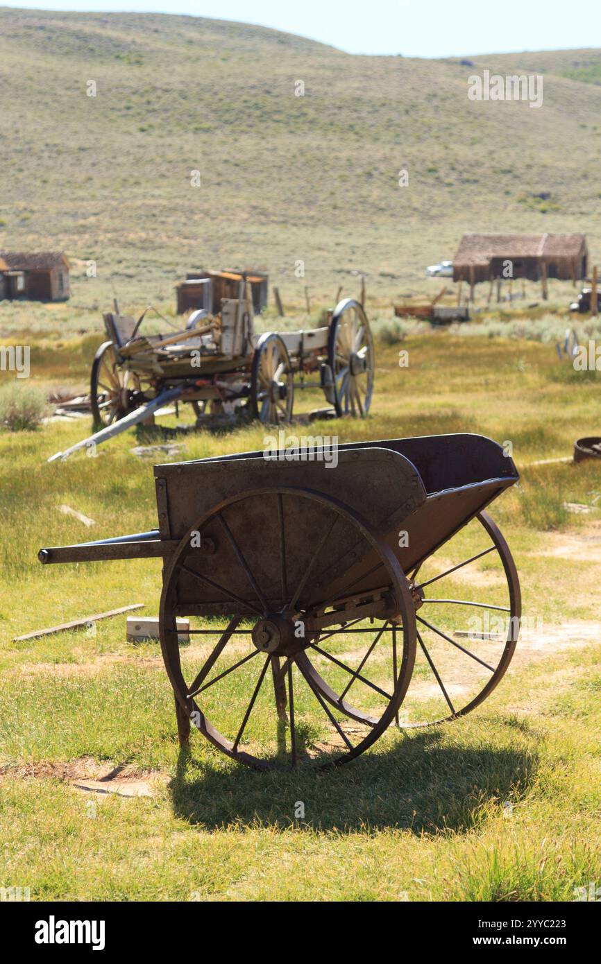 A rusted old wagon sits in a field. The wagon is surrounded by other ...