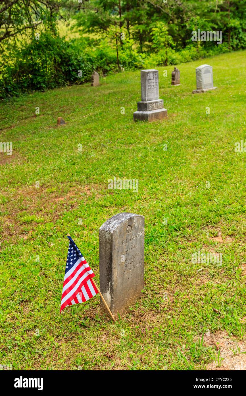 A small American flag is on a grave marker. The grave markers are in a ...