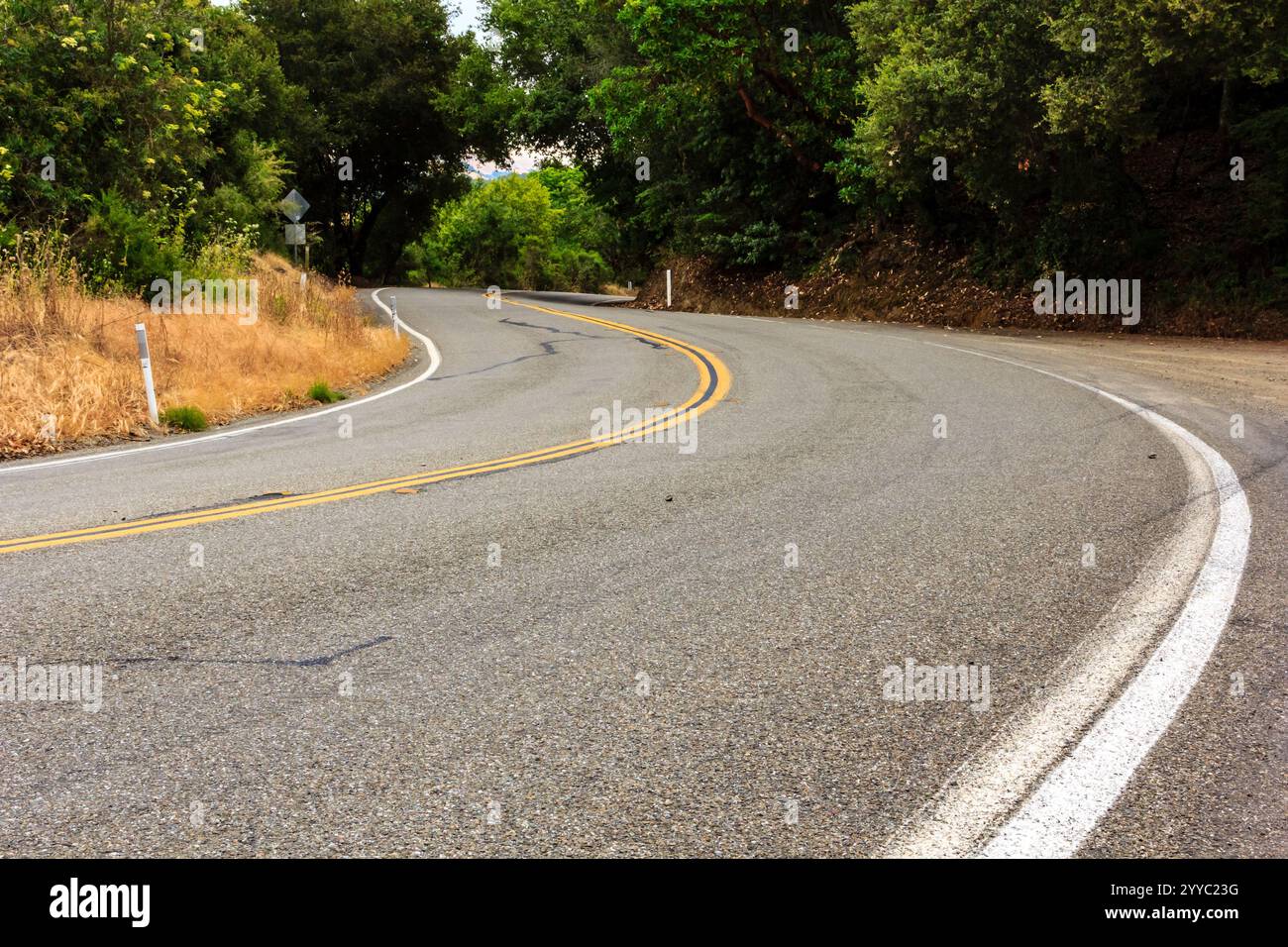 A road with a yellow line down the middle. The road is empty and ...