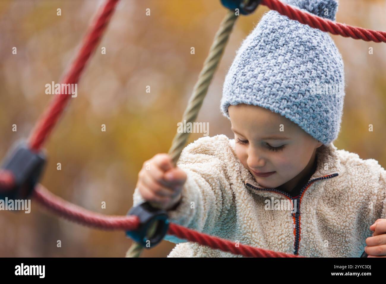 Child playing on a rope climbing structure at a playground in autumn ...