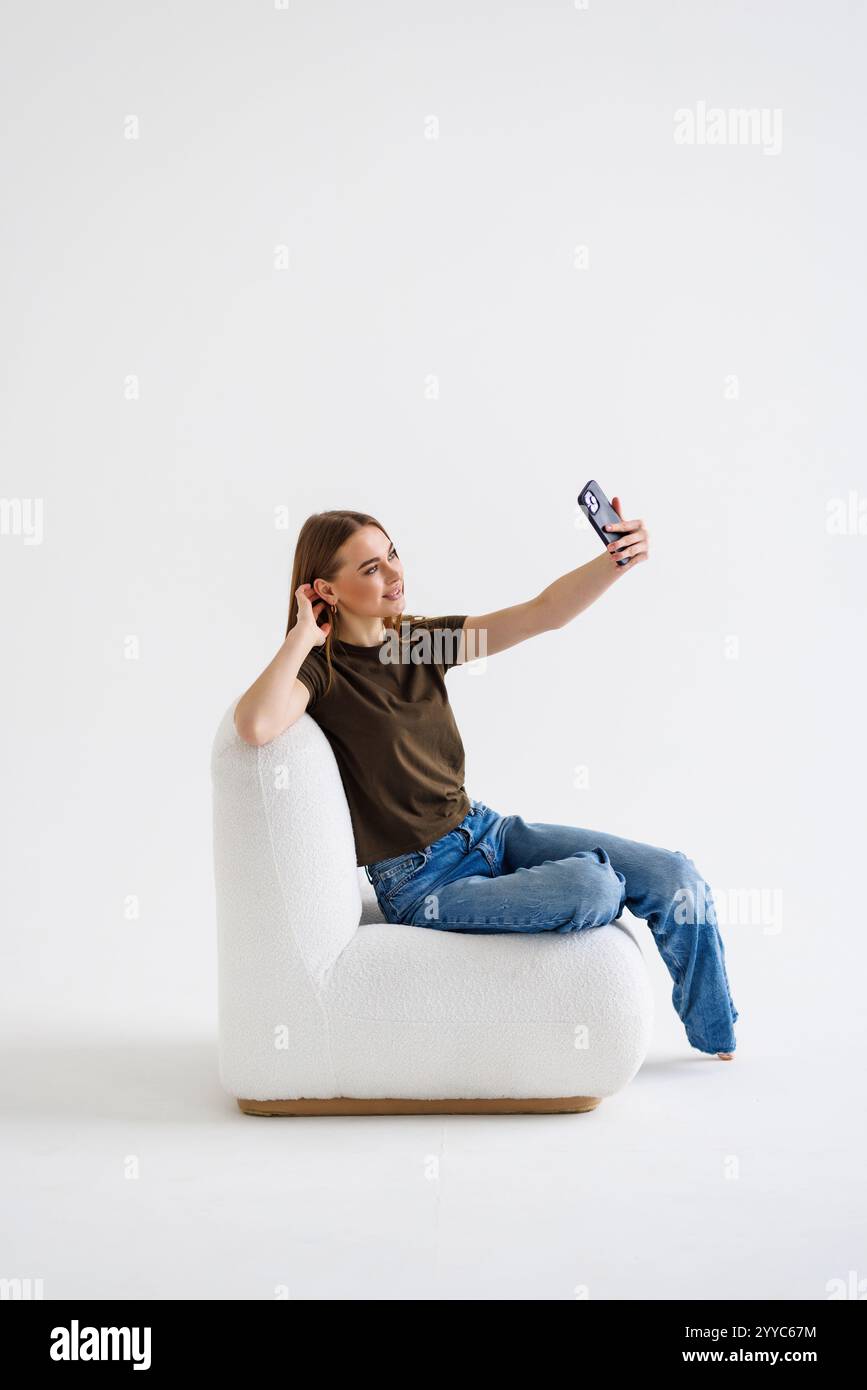Pretty young woman with smartphone and coffee taking selfie while ...