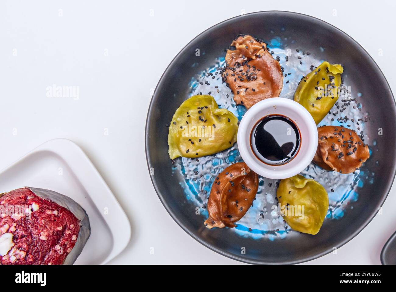 A black bowl with multi-colored gyozas, poppy seeds and soy sauce Stock ...