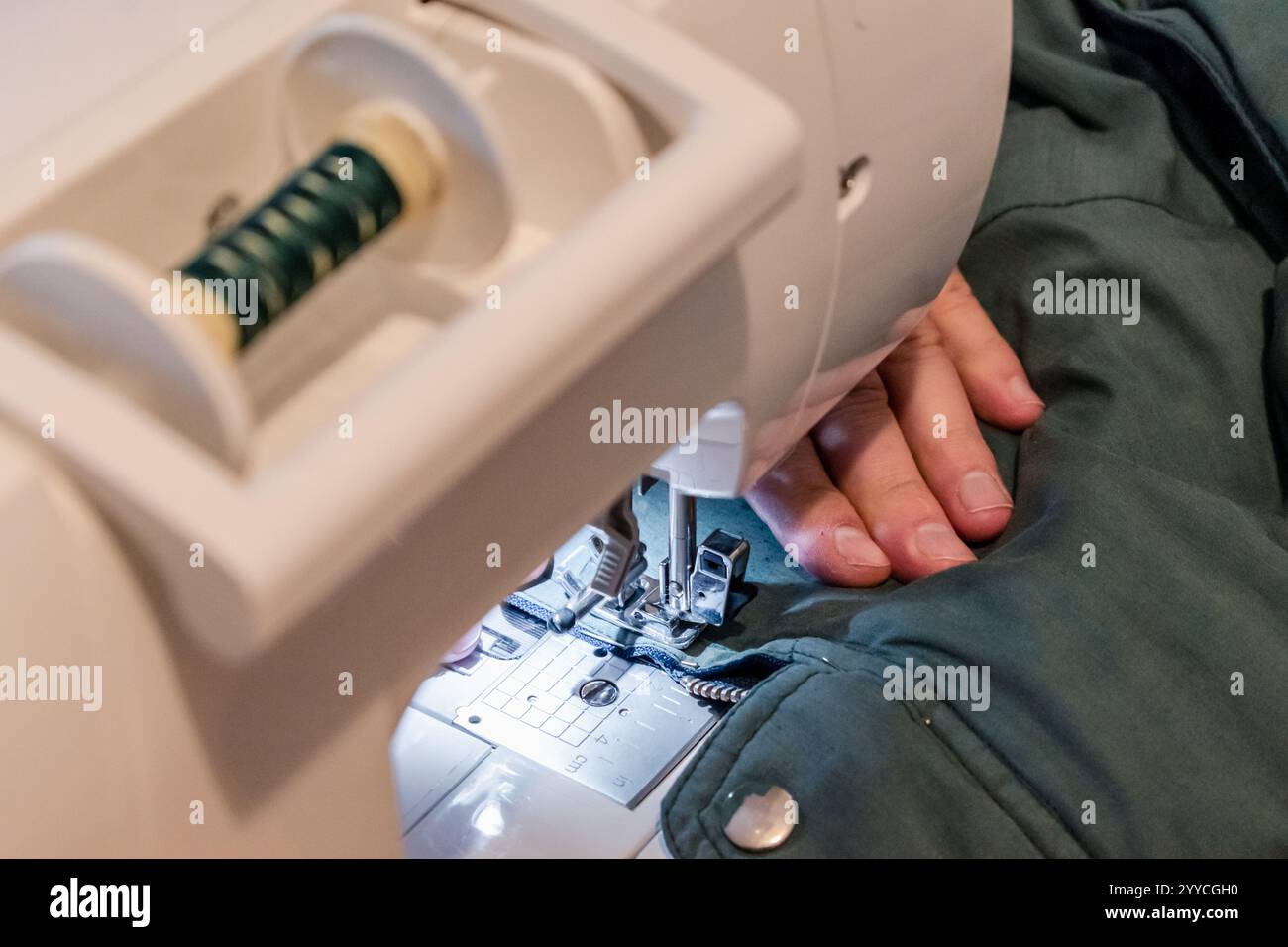 Man using a sewing machine with a garment, for repair work ...