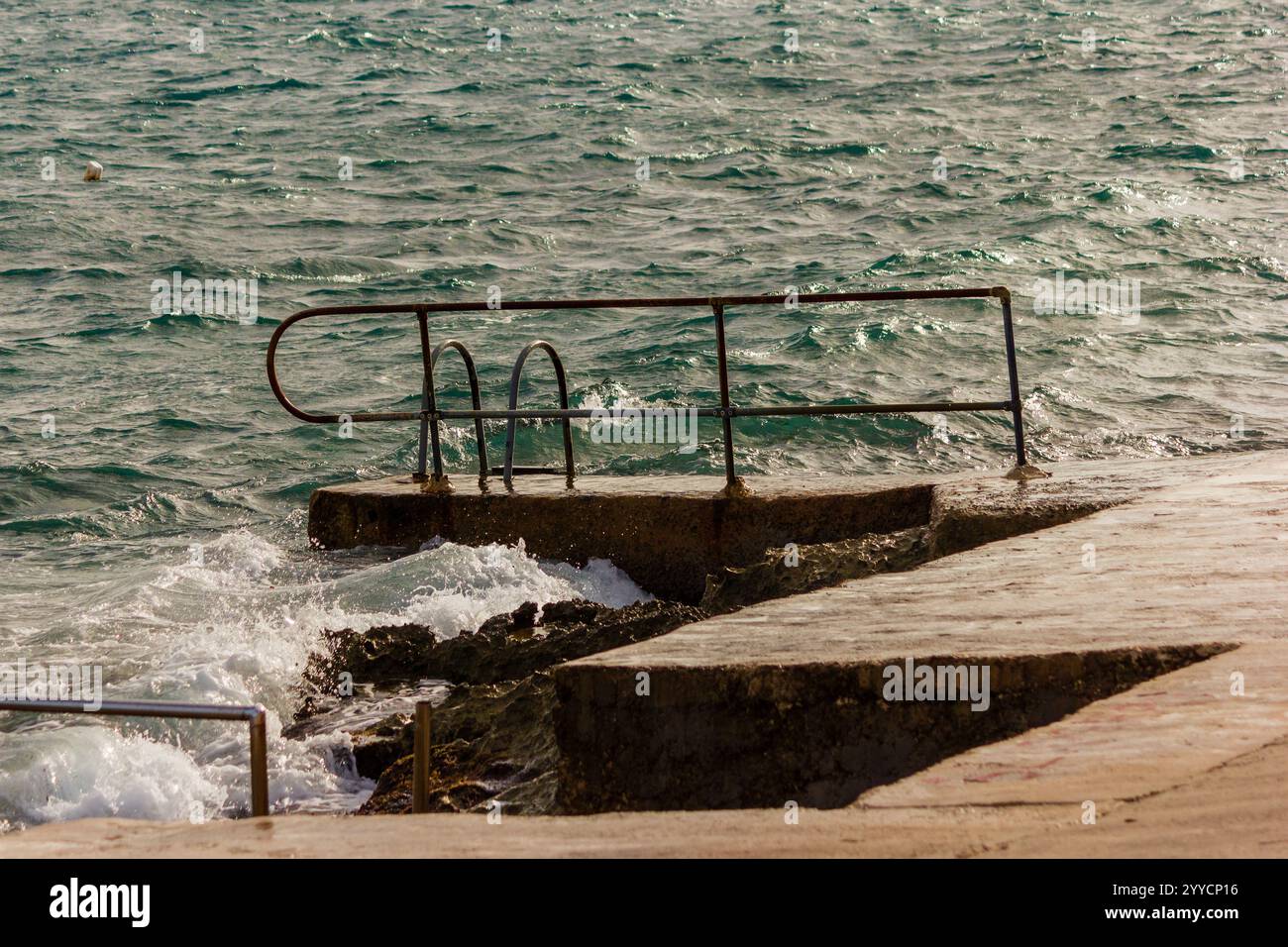 A serene seaside scene features a concrete pier with rustic railings ...