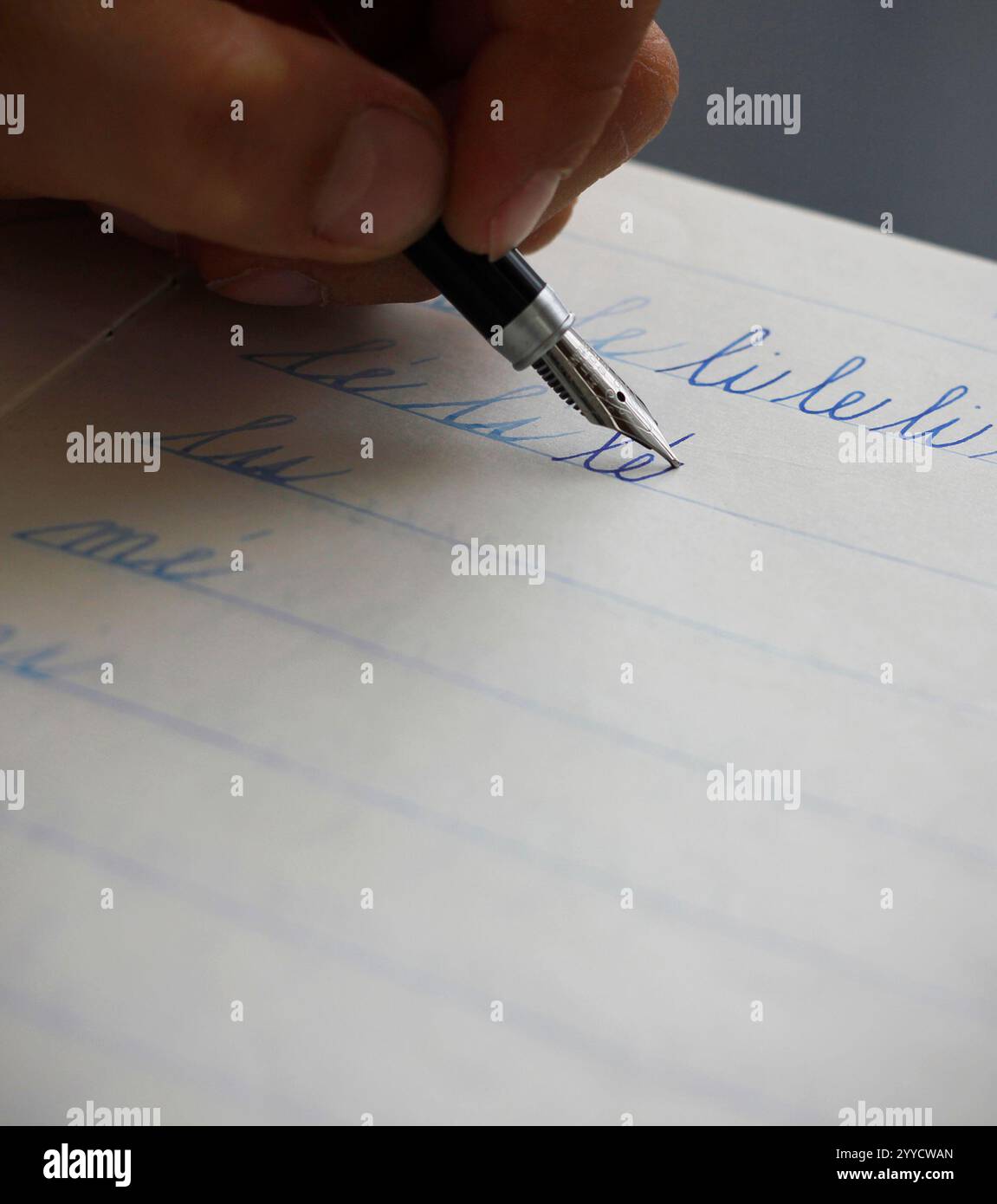 Detail of a child's left hand writing the syllables li and le with a ...