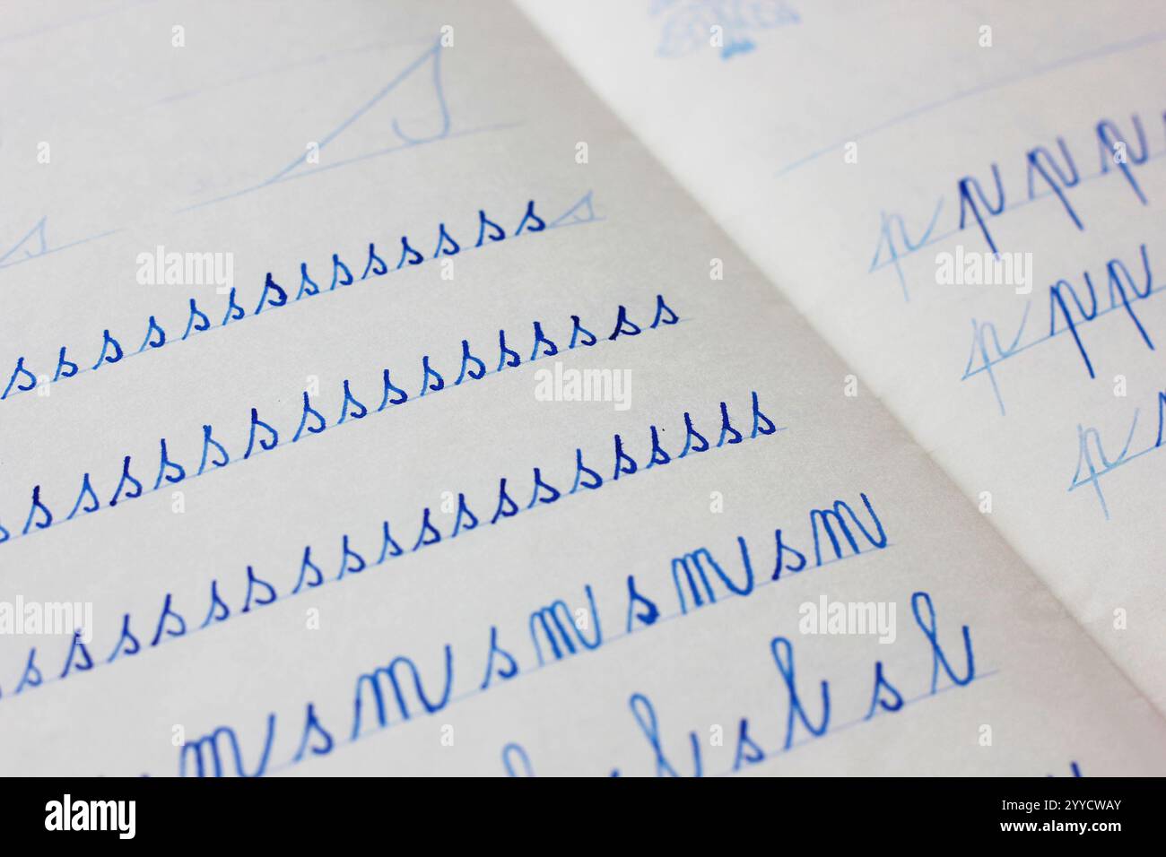 Close-up of blue letters written in cursive by a child in a paper ...