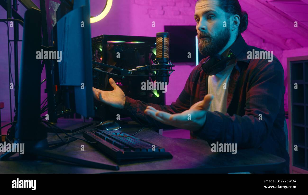 Caucasian gamer man addict puzzled influencer streaming play videogame blog computer screen ...