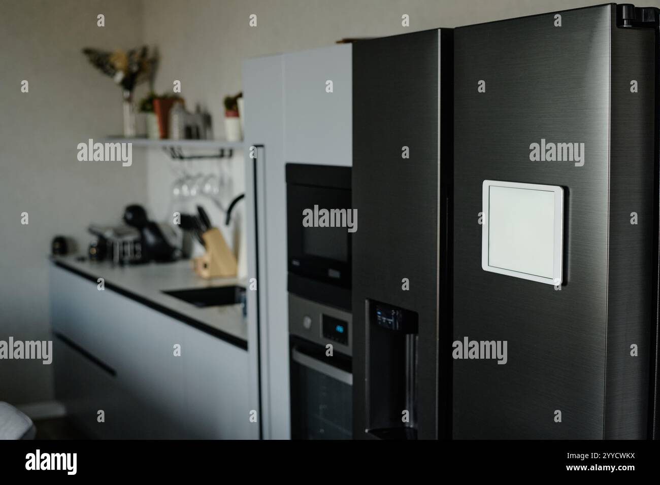 Black matte fridge with white tablet on its door in modern kitchen ...