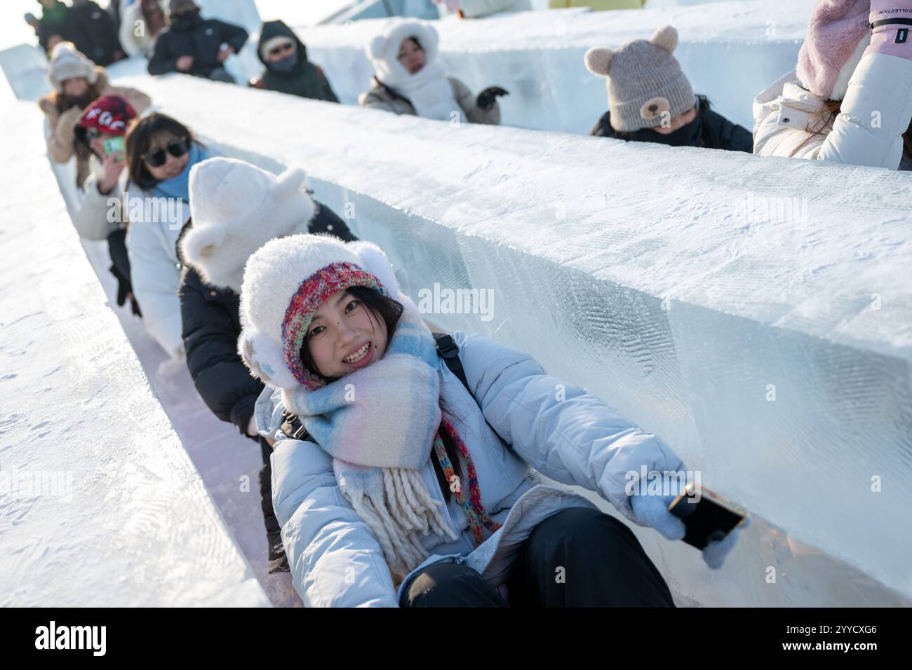 (241221) -- HARBIN, Dec. 21, 2024 (Xinhua) -- Tourists enjoy an ice ...