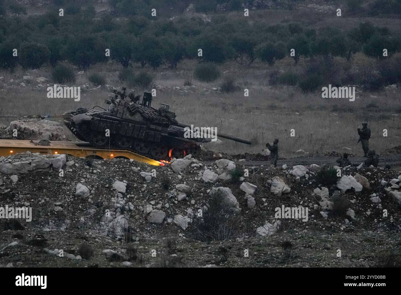 Israeli soldiers loads on a truck a Syrian tank inside the buffer zone ...