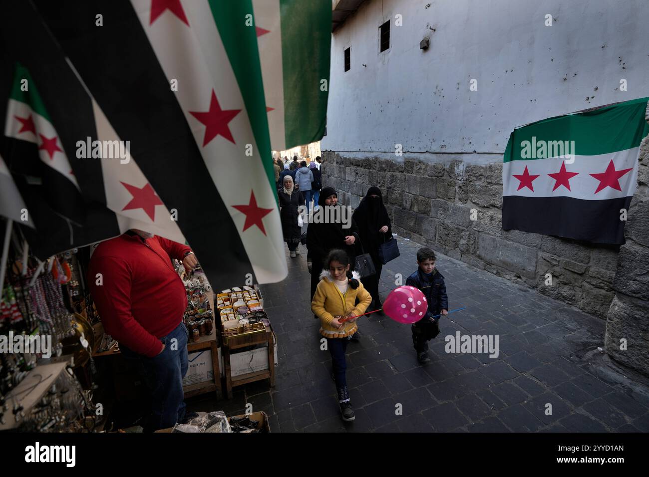 Syrian citizens walk next of the Syrian "revolutionary" flag, in old ...
