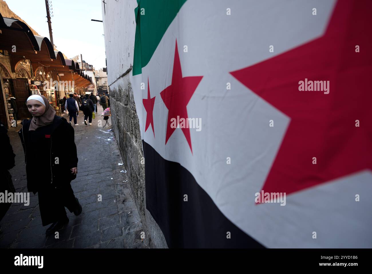A woman passes next the Syrian "revolutionary" flag that hanging on a ...