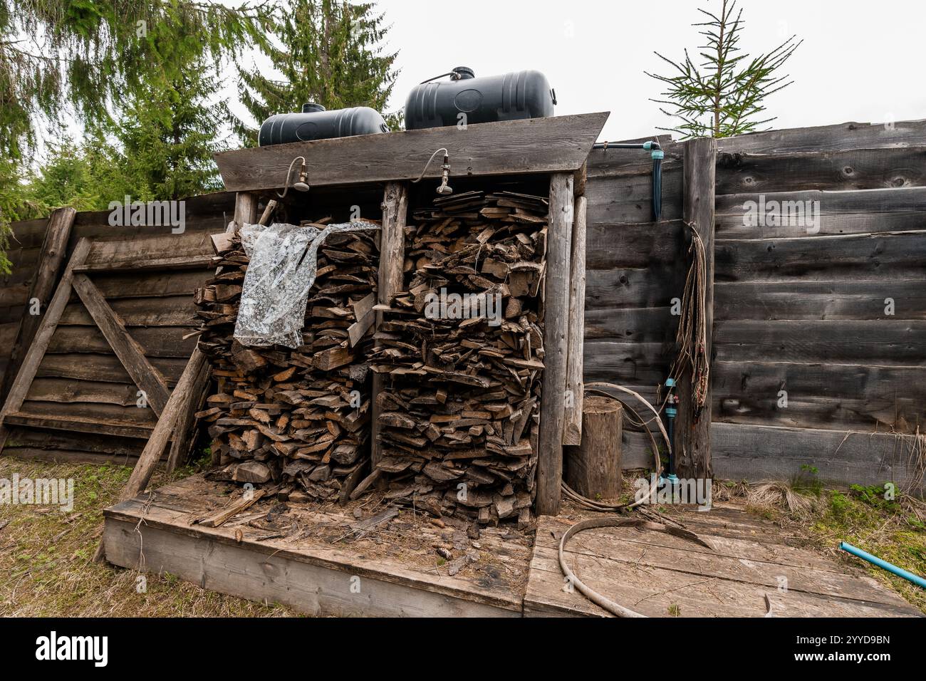 Stack of Firewood with Storage Tanks and Rustic Wooden Structure Stock ...