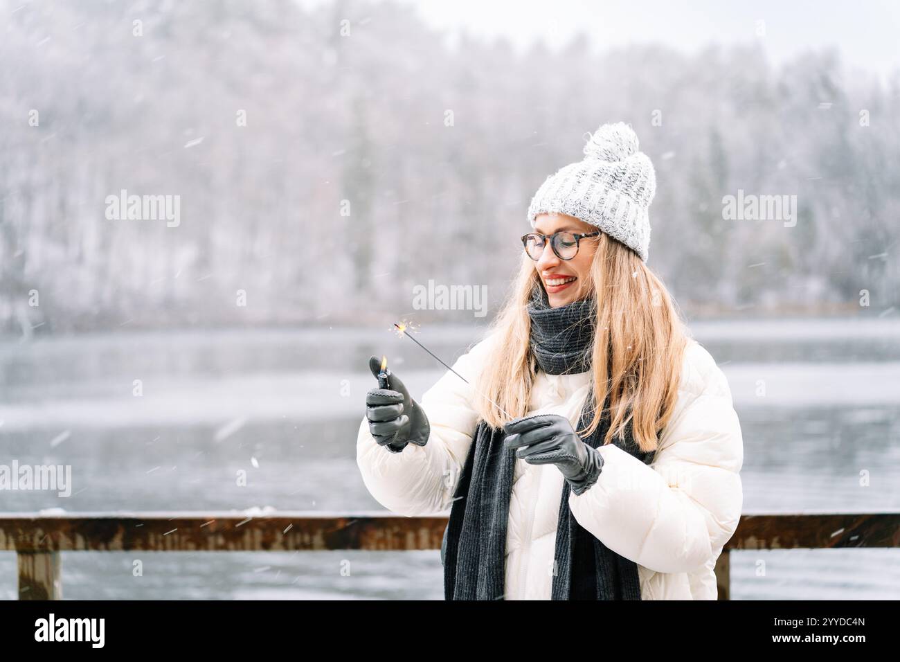 woman preparing to light sparklers with a pocket lighter on a snowy ...