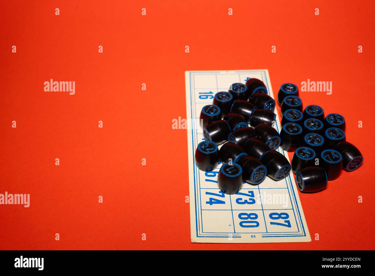 Black bingo balls with blue numbers rest on an orange background next ...