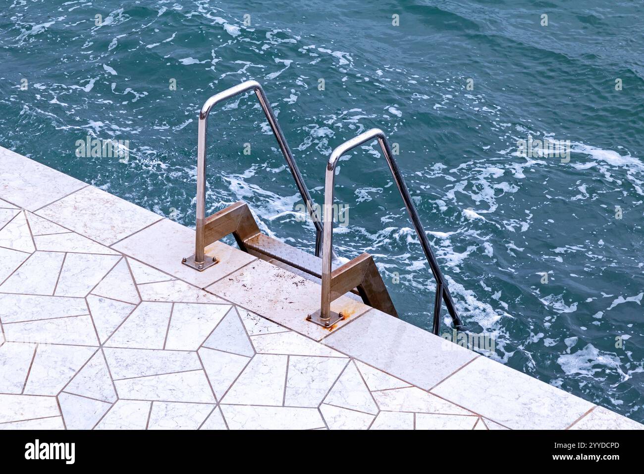 Metal hand rail used by people to enter sea coast Stock Photo - Alamy