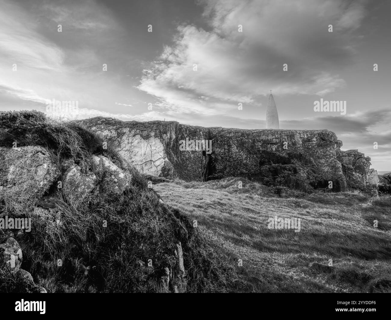 High-angle view of a coastal landscape. A slender white tower perches ...