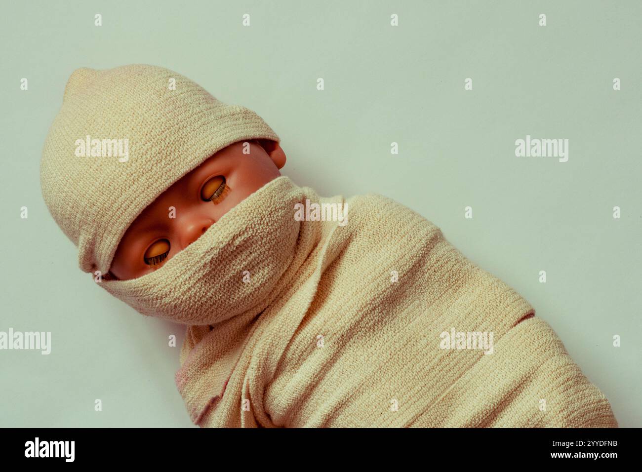 The doll the baby is wound with fabric. The body of the child is ...