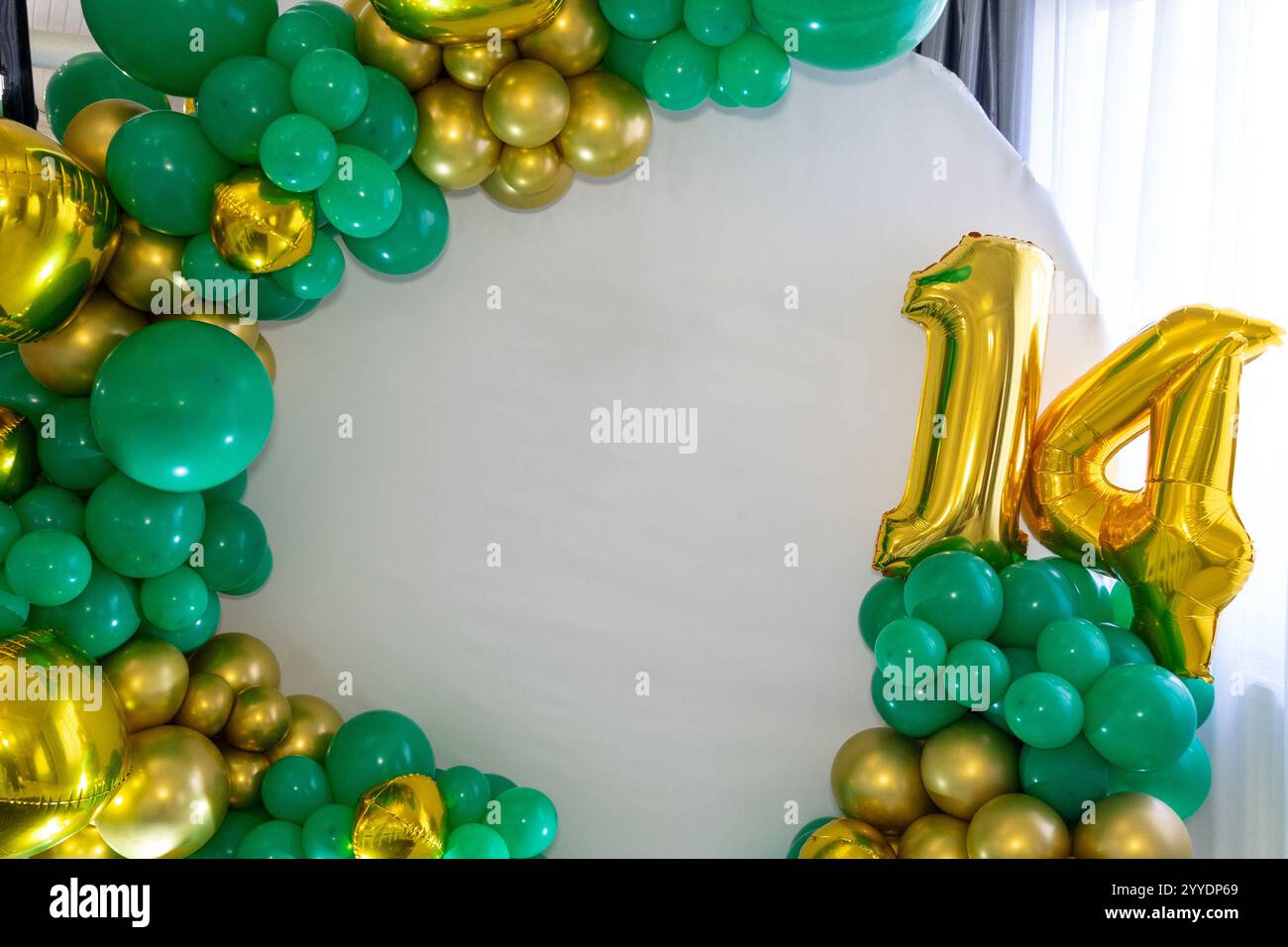 A vibrant balloon arch features green and gold hues, highlighting the ...