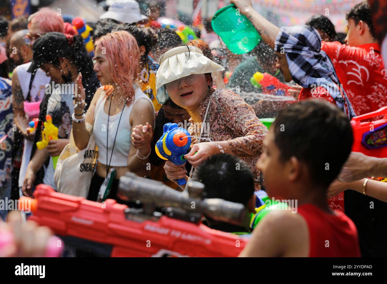 Bangkok, Thailand - April 13, 2023: Revelers splash water in each other using water guns during ...