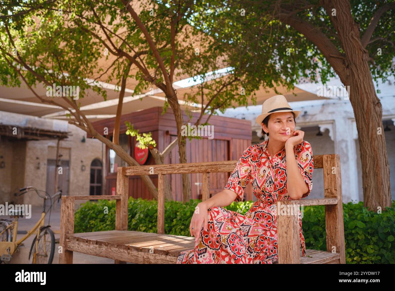 Young woman in an ethnic dress and hat exploring Al Seef Park in Dubai ...