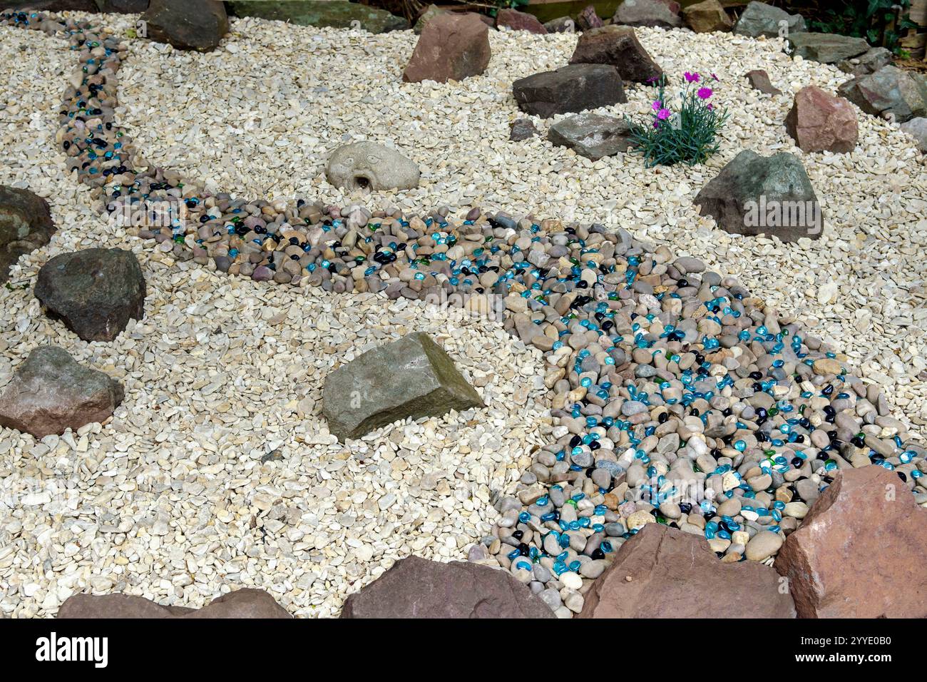 Rockery in garden with fake river made of glass coloured pebbles and ...