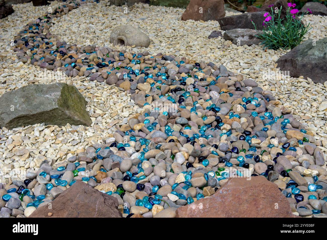 Rockery in garden with river made of glass coloured pebbles and stones ...