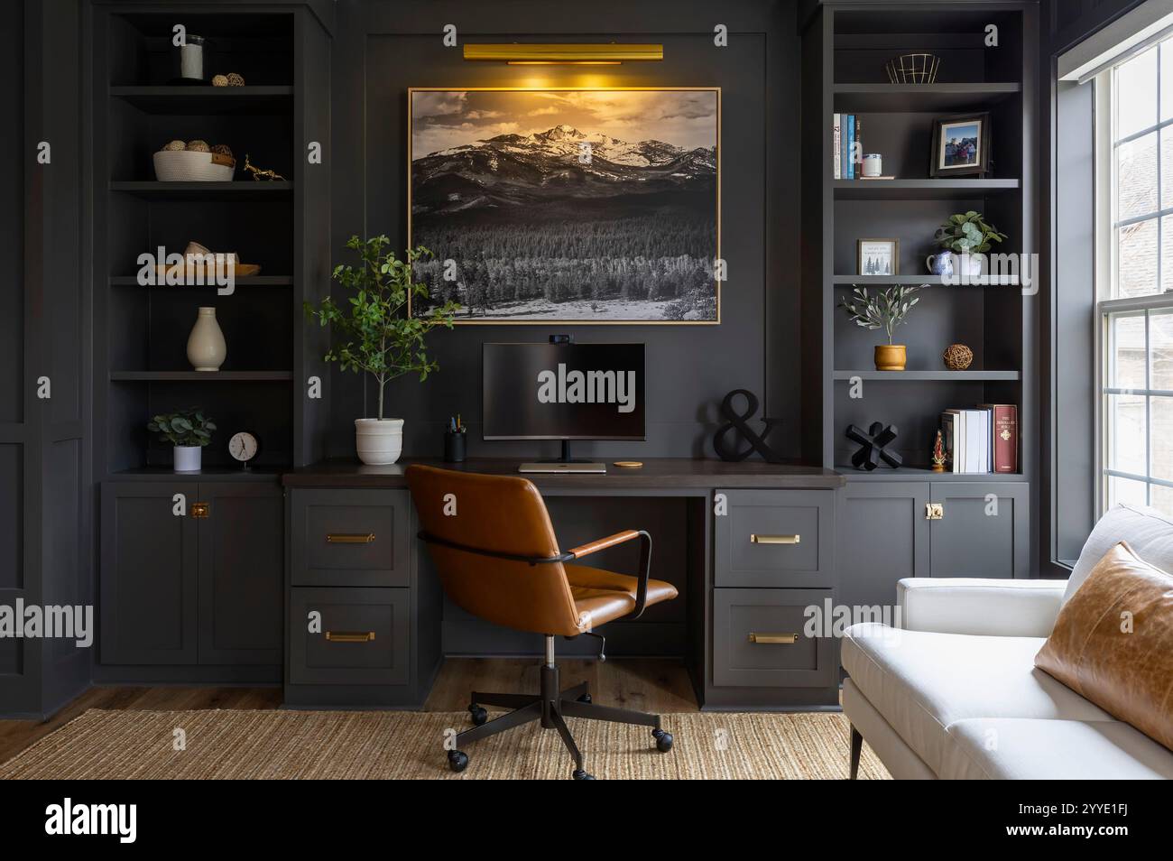 Dark gray paneled home office with built-in desk and cabinets Stock ...