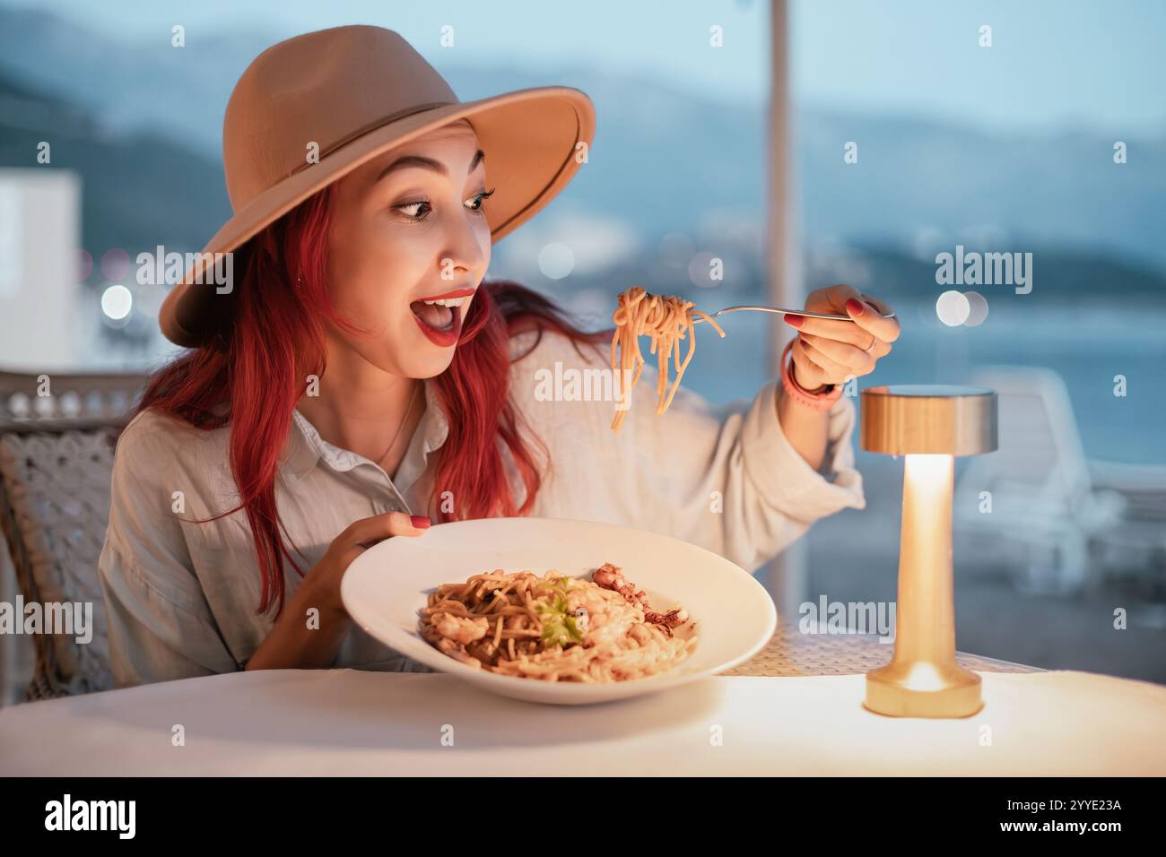 Excited tourist enjoying delicious pasta in a restaurant by the sea ...