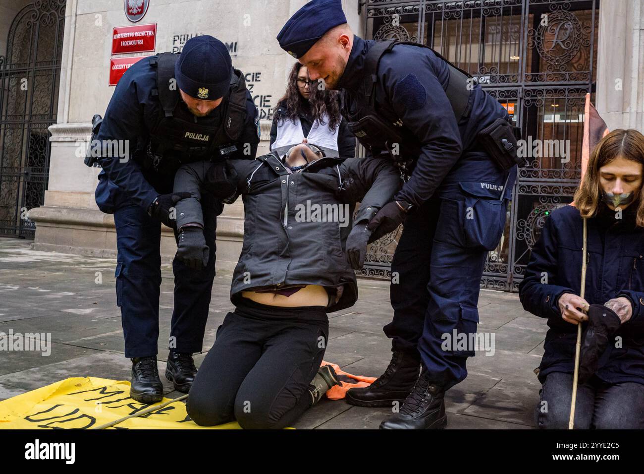 Police officers carry an activist away from the protest. Activists from ...