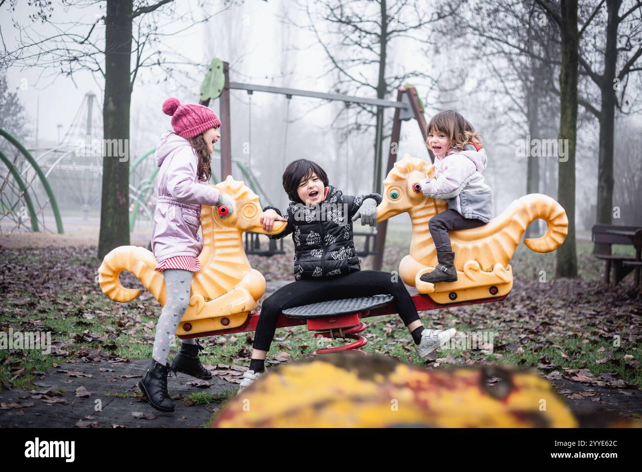three little girls playing at children's playground having fun on a ...
