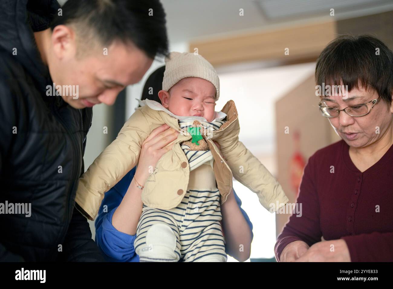 A 6-month-old boy with a pacifier stays indoors with his grandmother ...