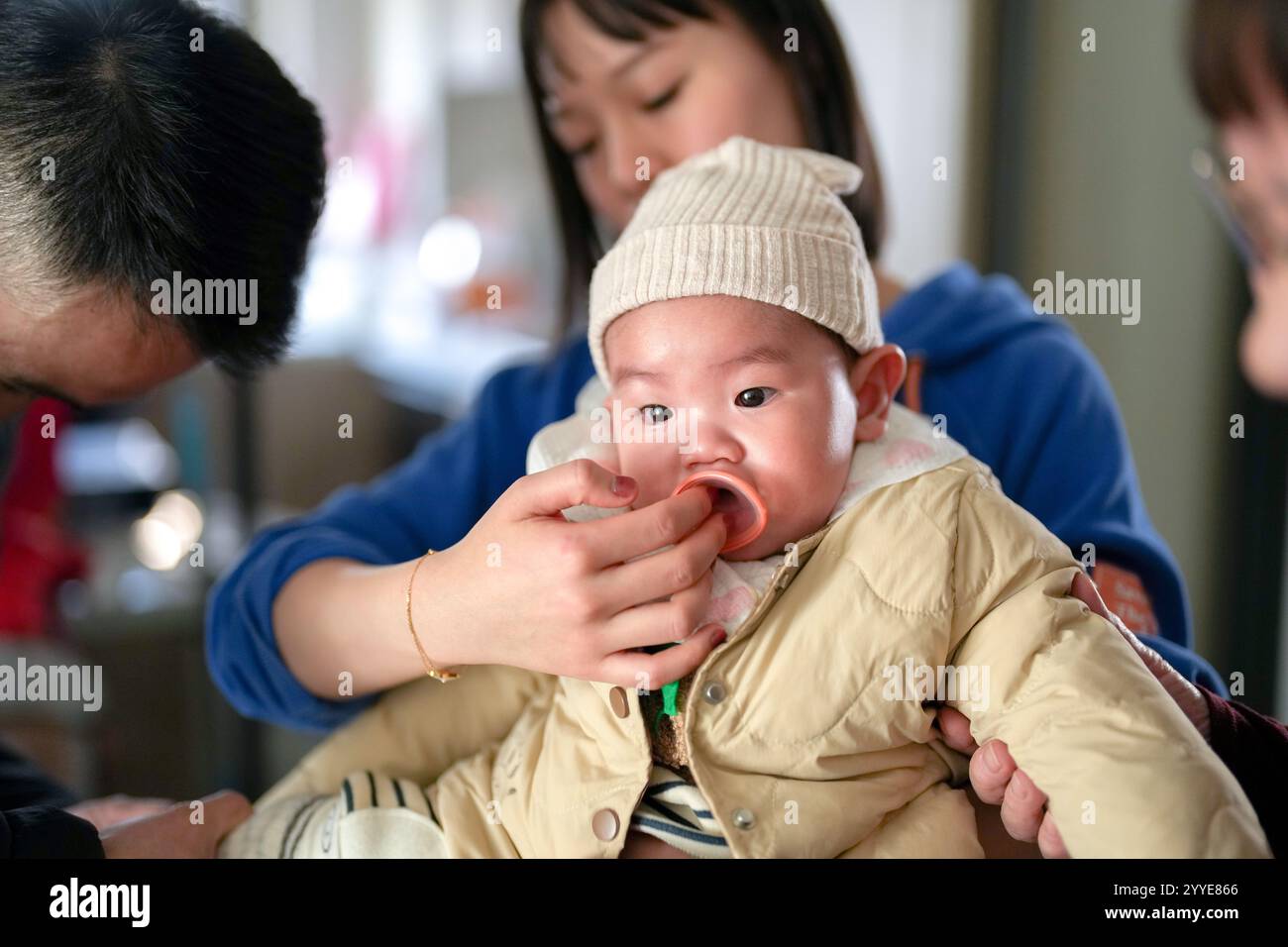 A 6-month-old boy with a pacifier stays indoors with his grandmother ...