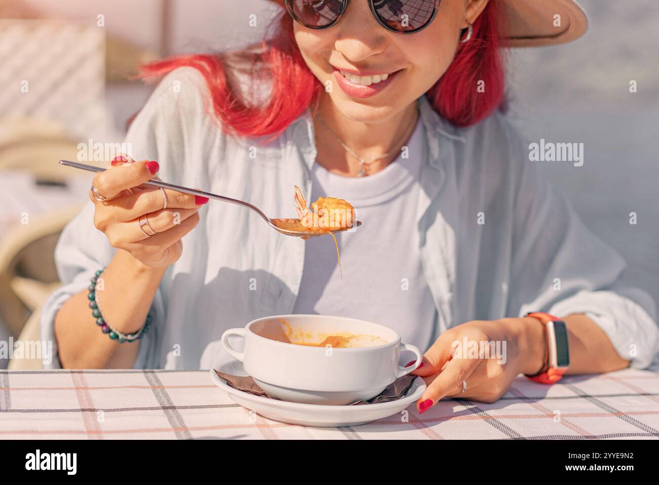 Happy tourist eating delicious seafood soup in an outdoor restaurant ...