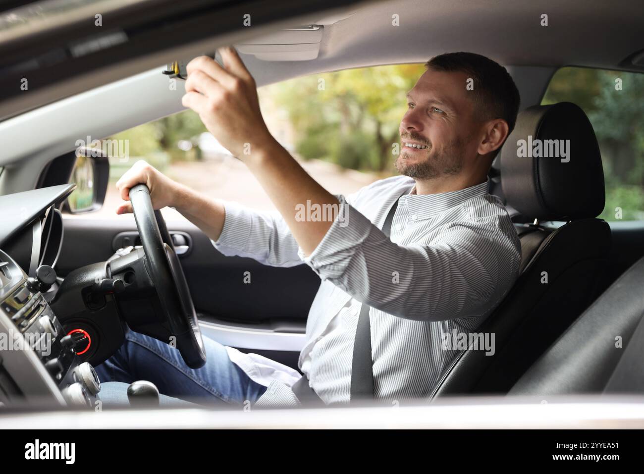 Man adjusting rear-view mirror in car before driving Stock Photo - Alamy