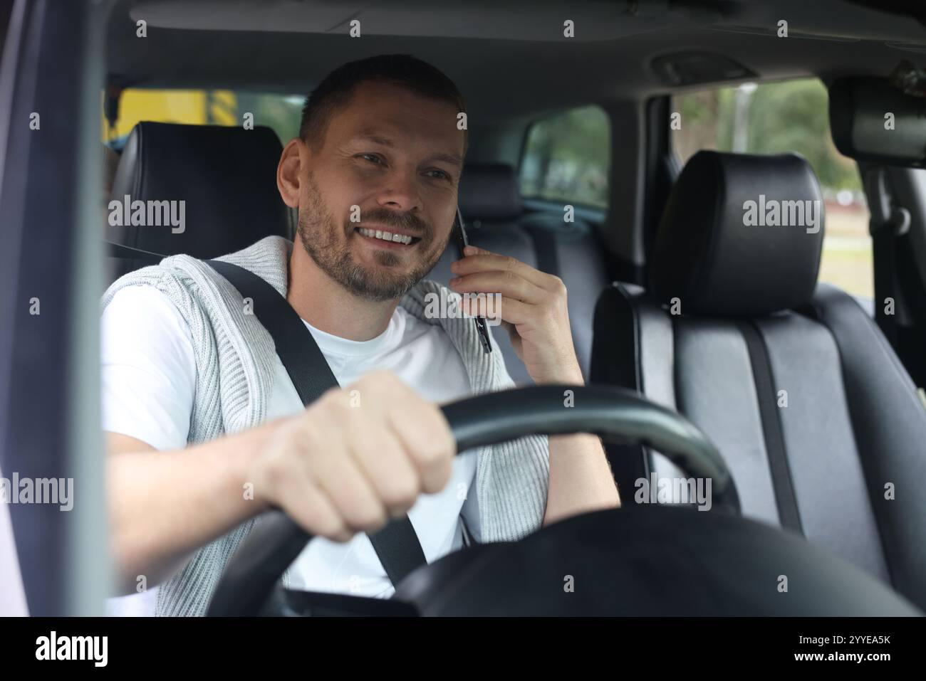 Man talking on phone while driving modern car, view through windshield ...