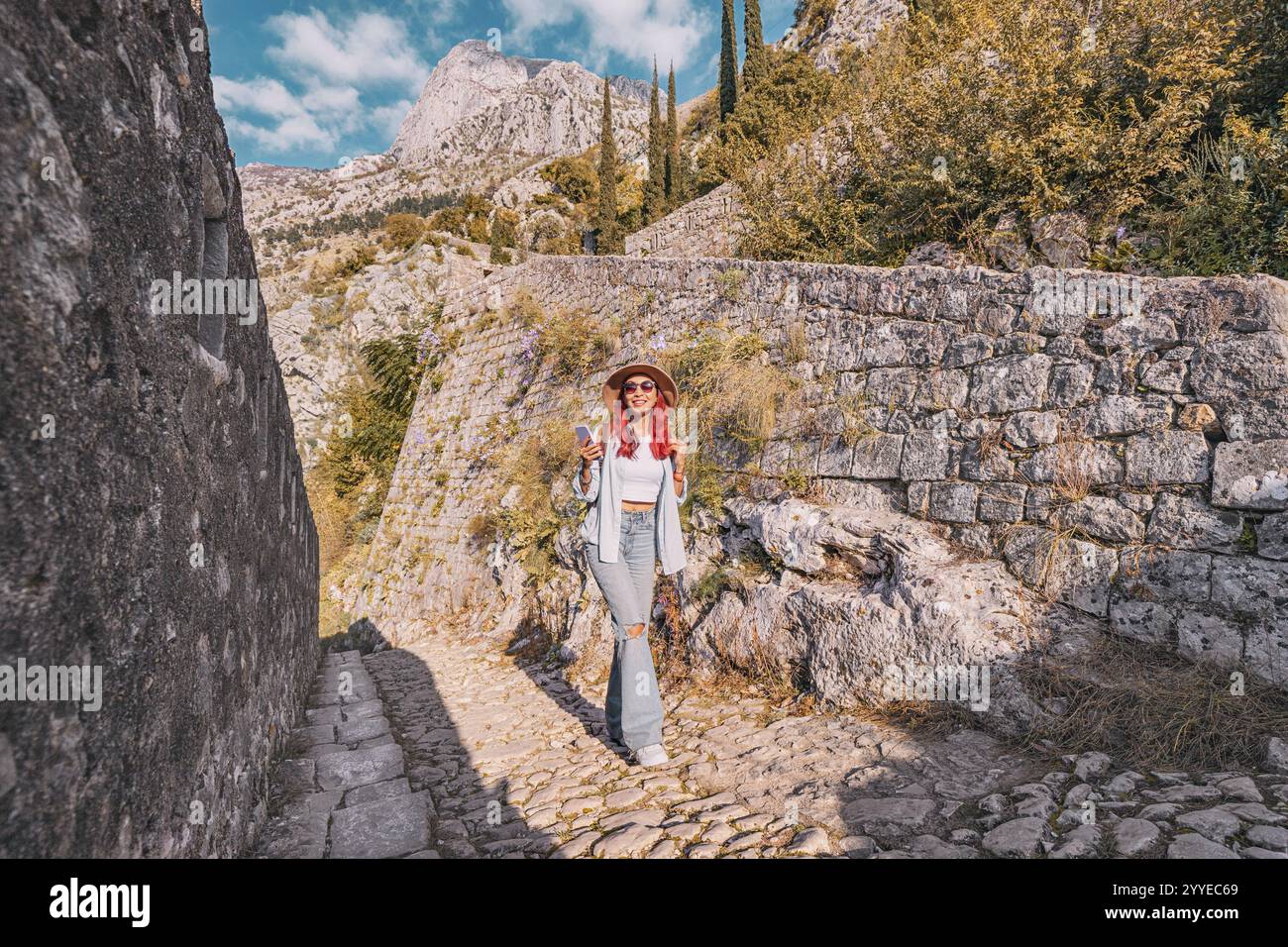 Young woman tourist walking up cobblestone path in historic town of ...