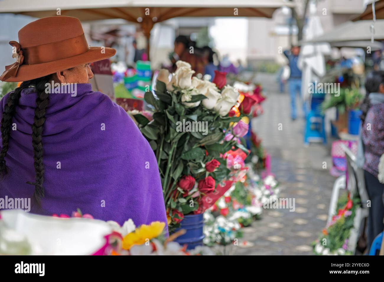 Woman in traditional attire arranging colorful roses in buckets at a ...