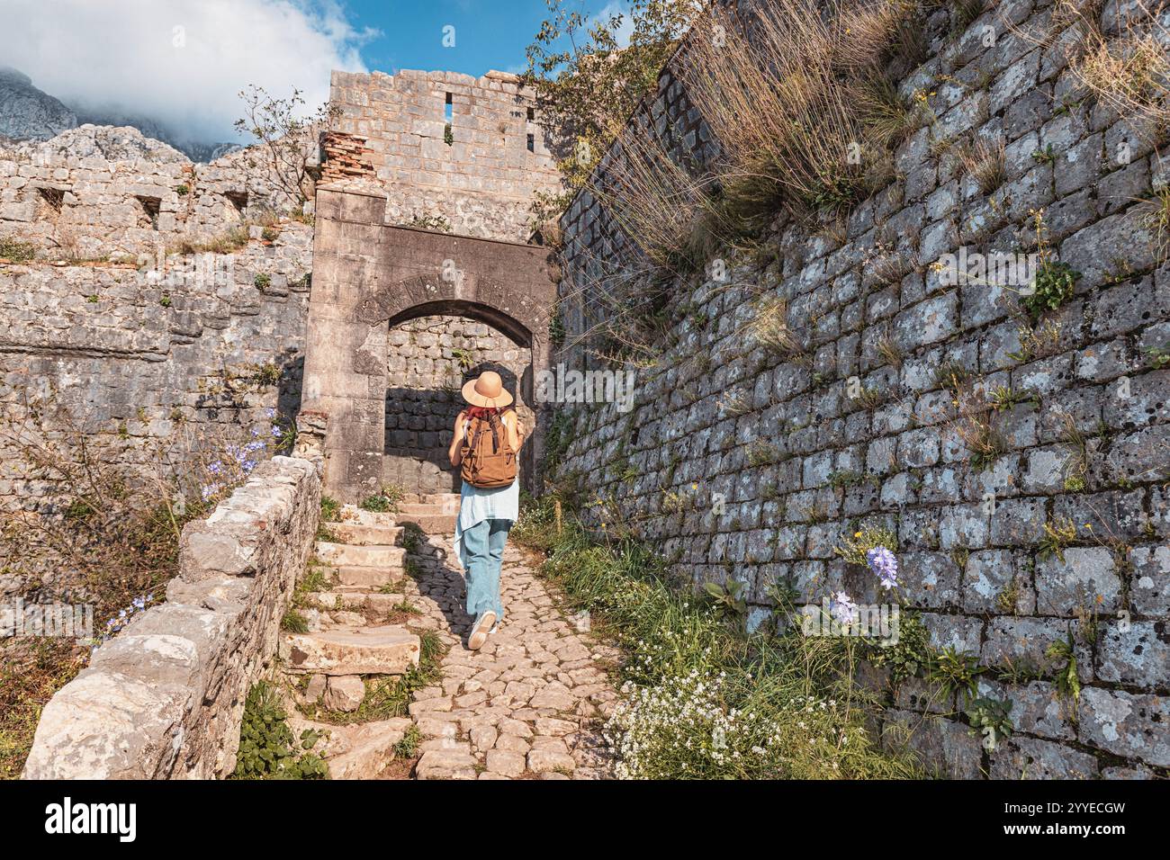 Female tourist wearing hat and backpack exploring ancient ruins of ...