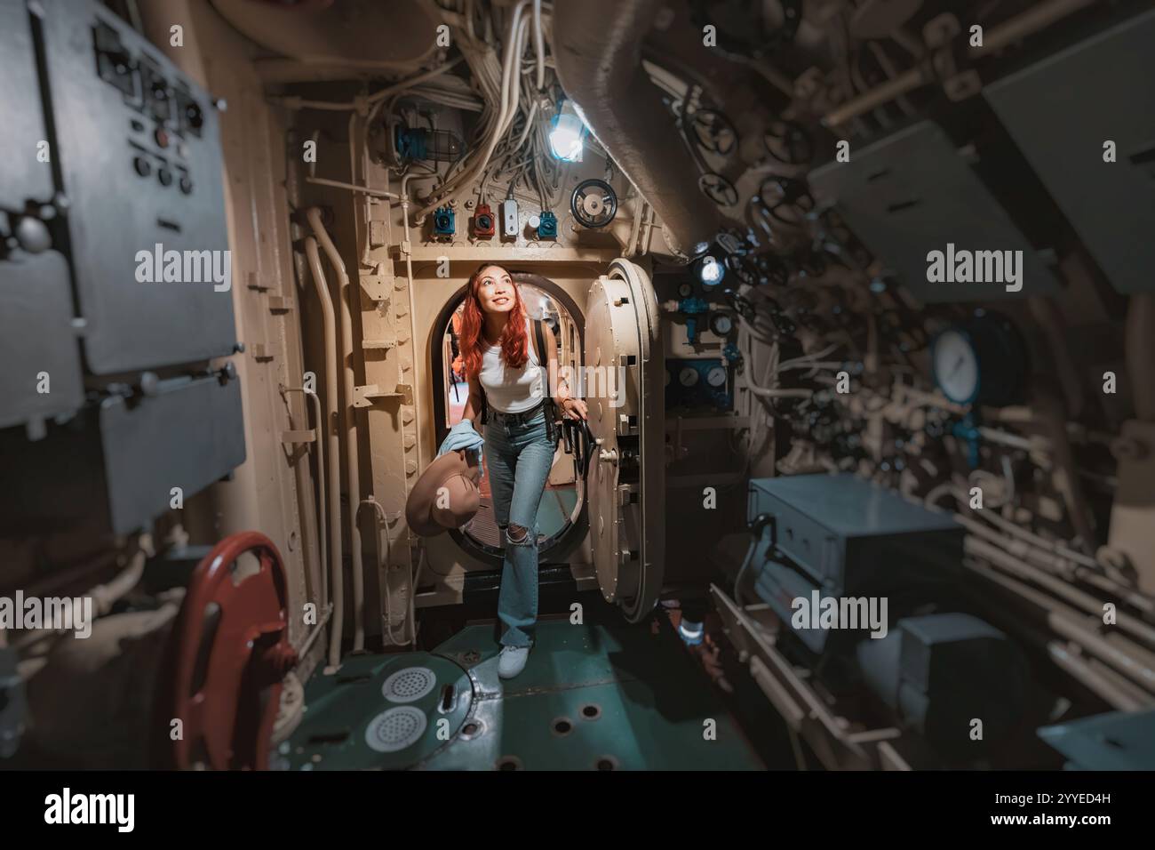 Young woman entering a submarine through a hatch, exploring the ...