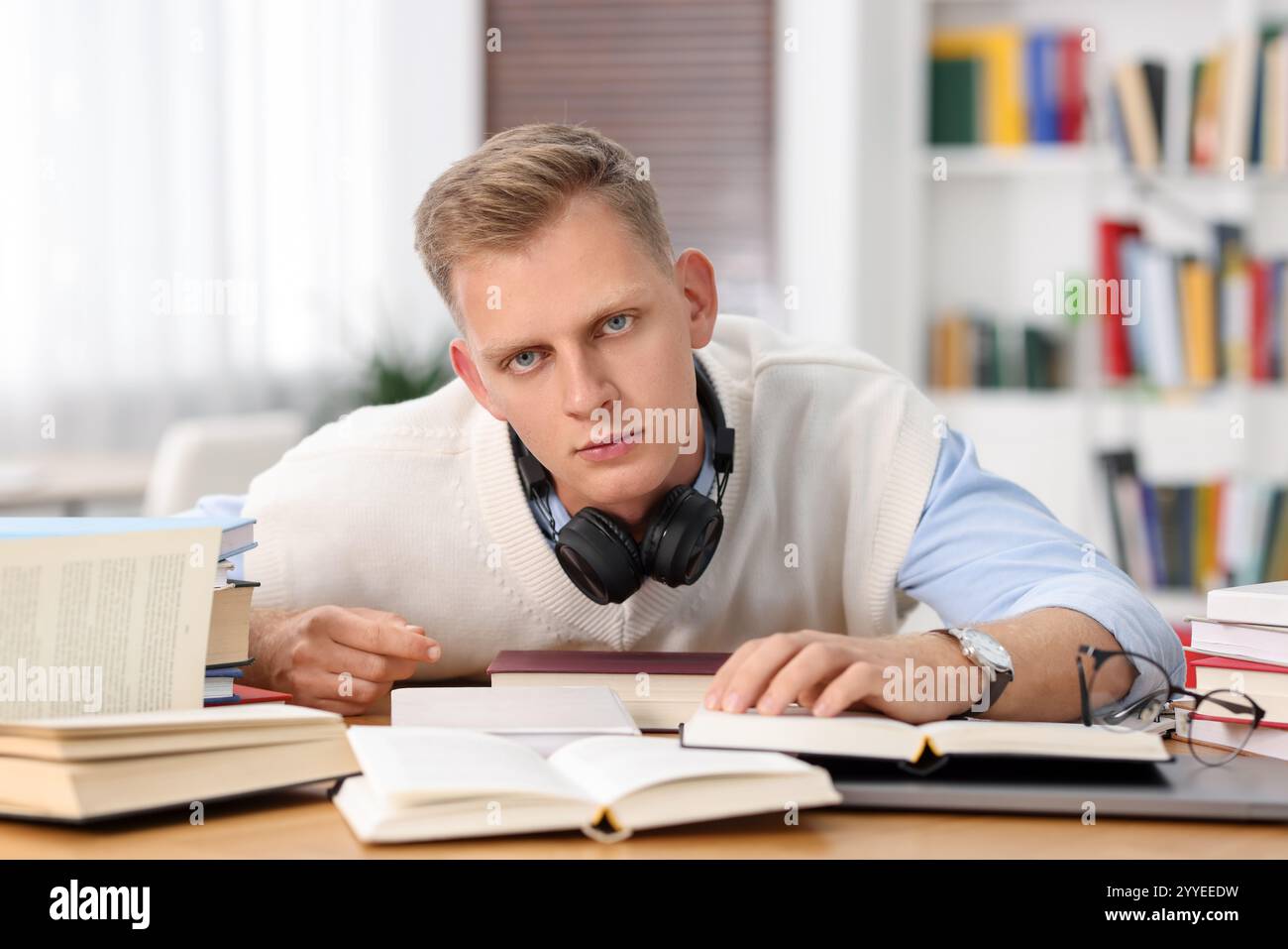 Preparing for exam. Tired student with books at table indoors Stock ...