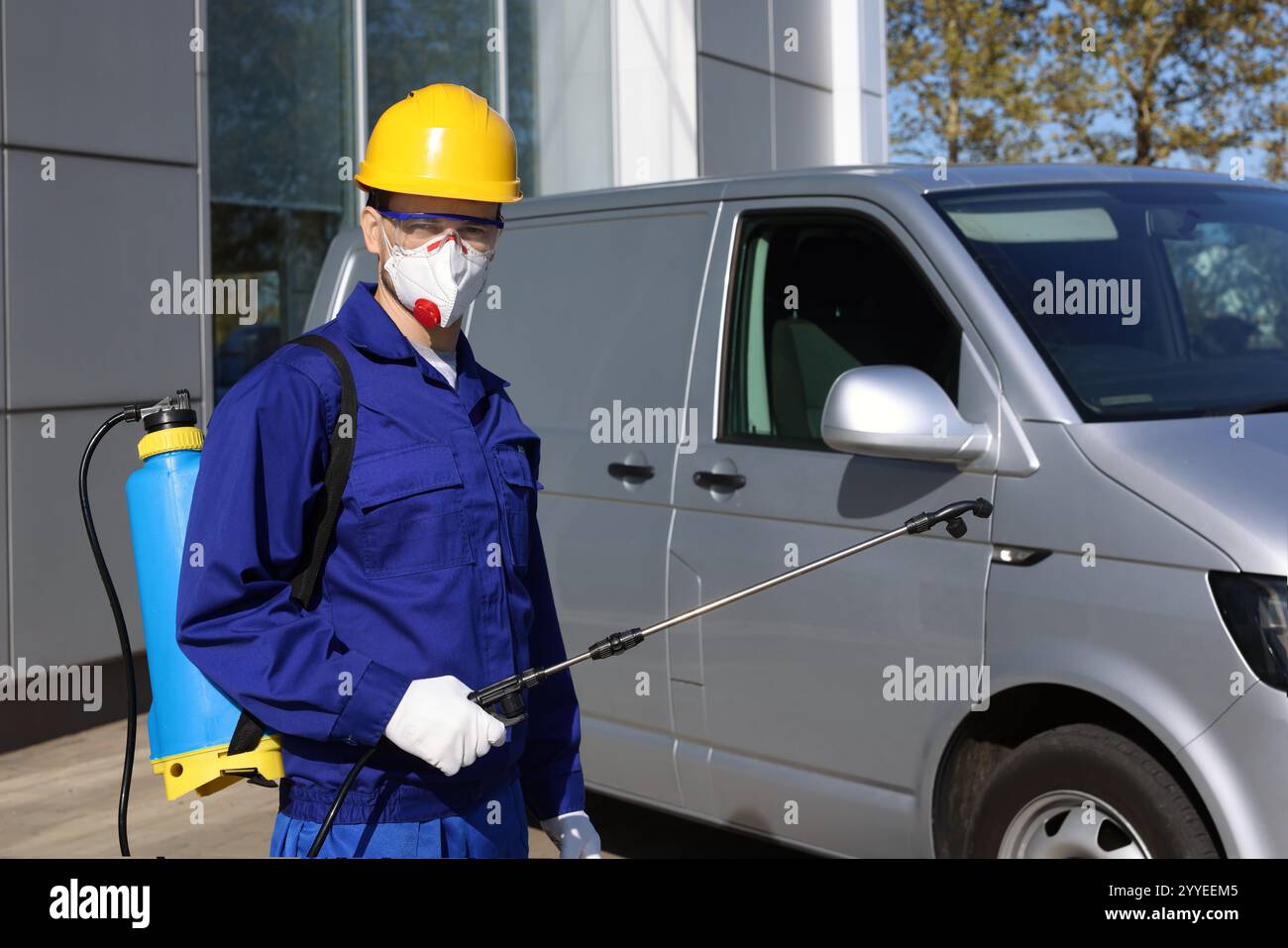 Pest control worker with spray tank near gray minibus outdoors Stock ...