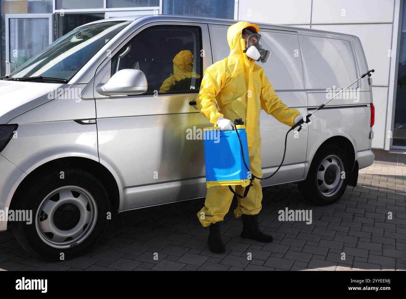 Pest control worker with spray tank near gray minibus outdoors Stock ...